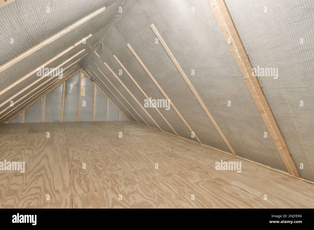 Interior of empty attic with light wooden floor under roof of new house ...