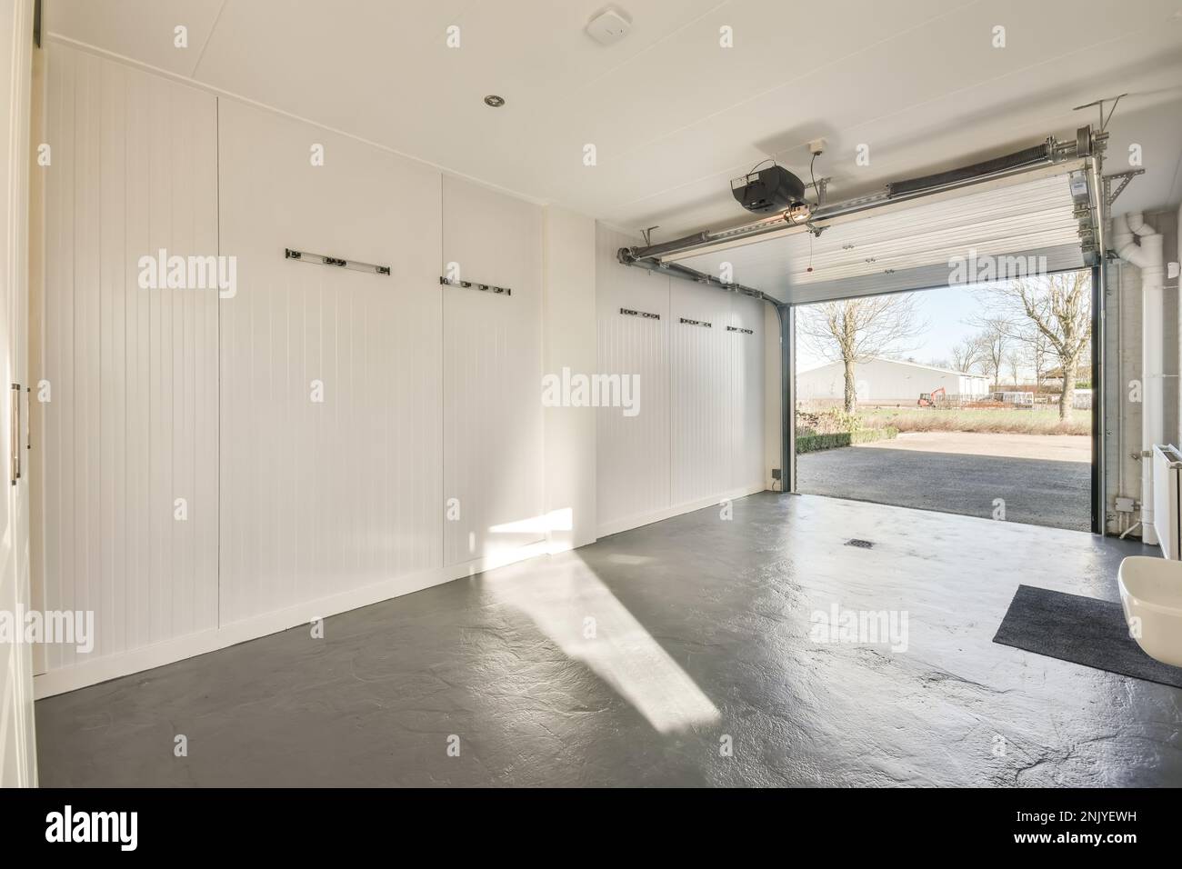 Interior of empty spacious garage with opened door on sunny day in ...