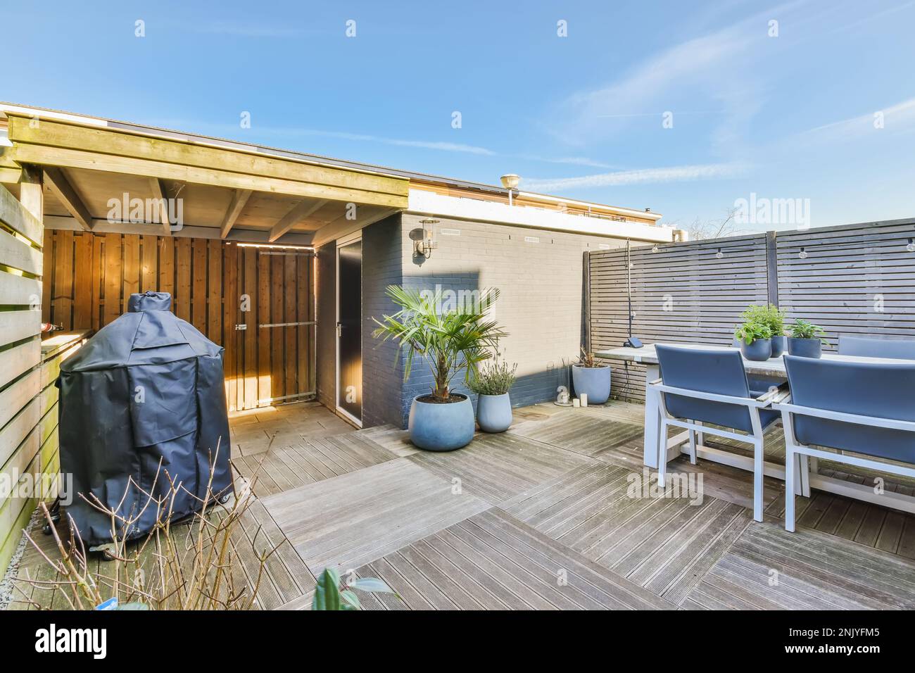 Modern terrace with table and chairs placed against fence near open ...
