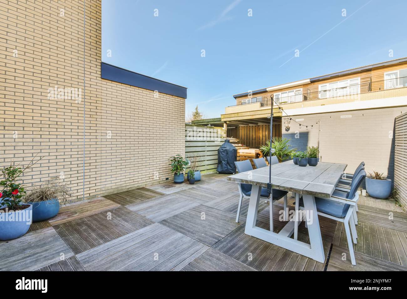 Modern terrace with table and chairs placed against fence near open ...