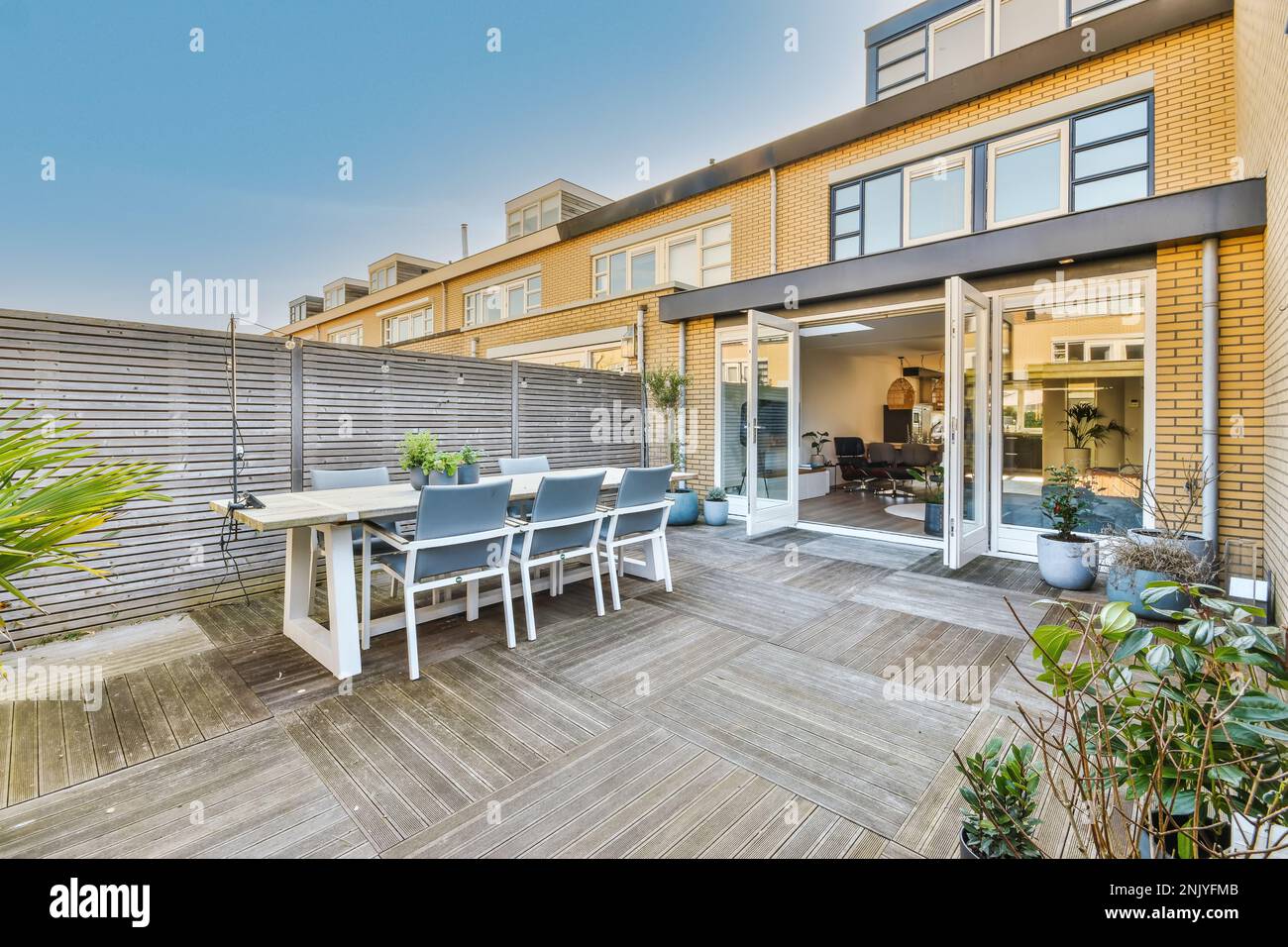 Modern terrace with table and chairs placed against fence near open ...