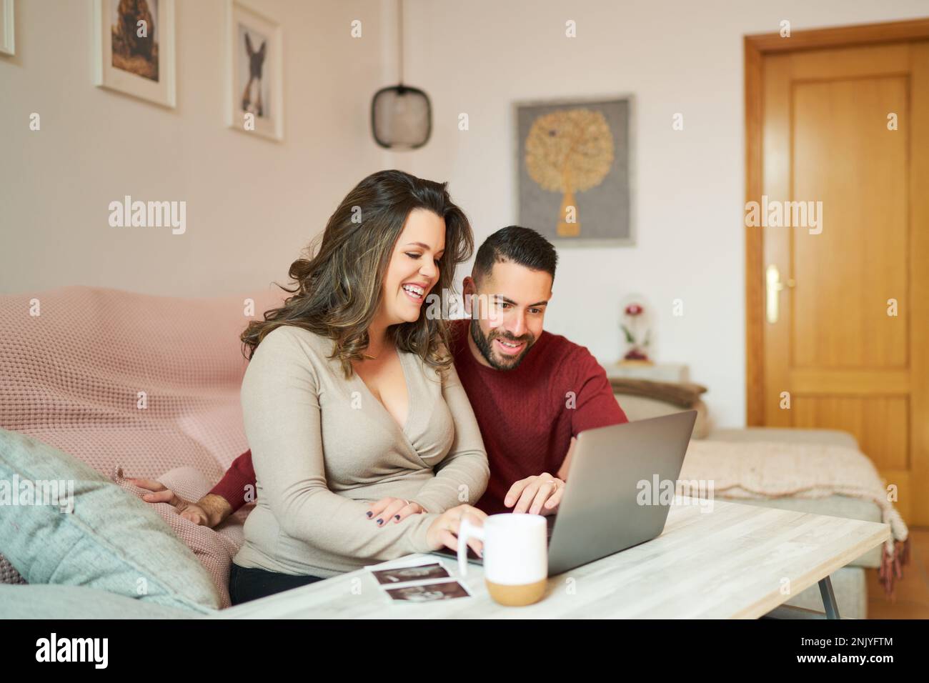 Side view of smiling bearded husband in red sweater sitting near happy ...