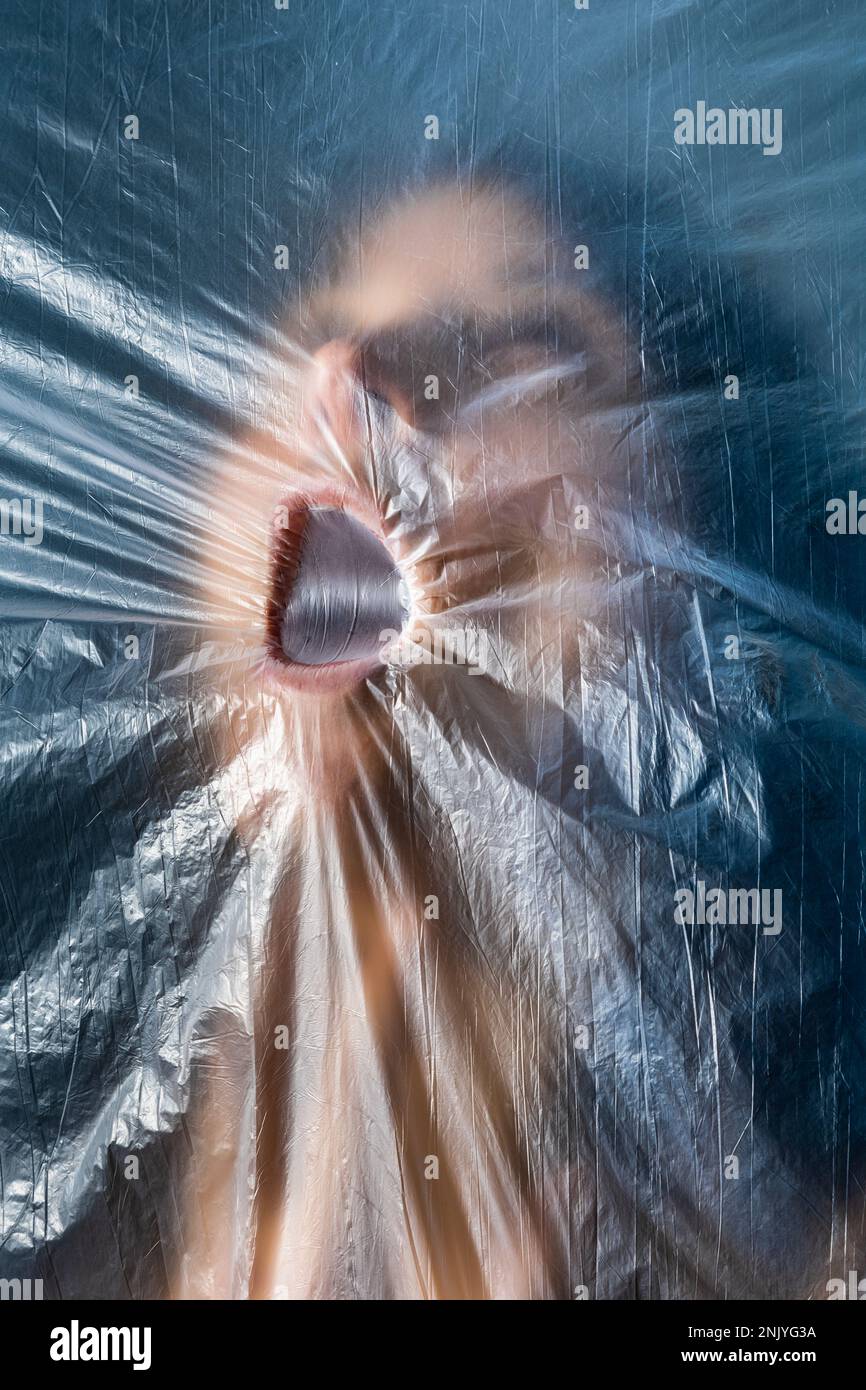 Female standing behind transparent plastic film lack of oxygen while ...