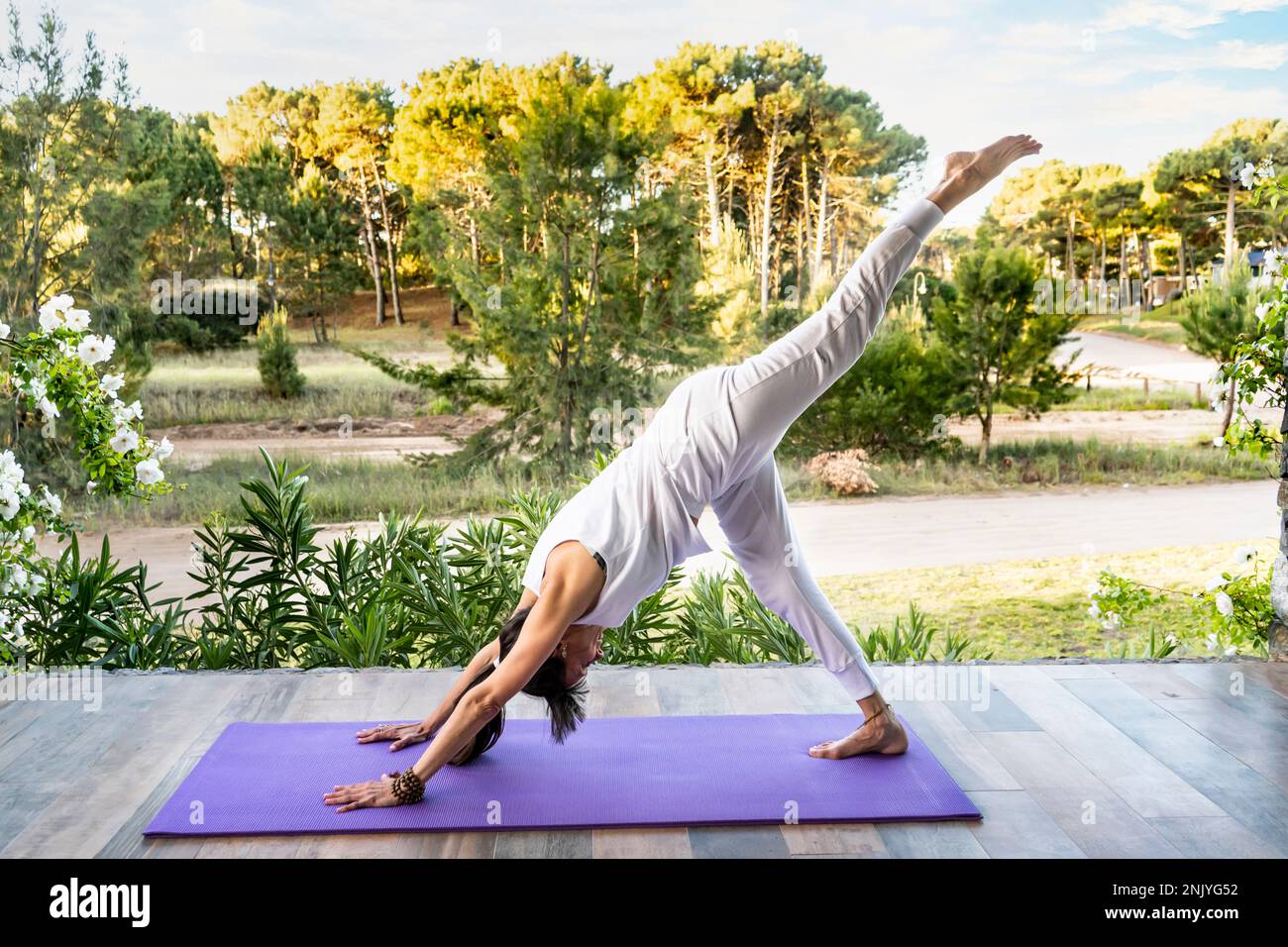 Full body side view of flexible barefoot female in white activewear ...