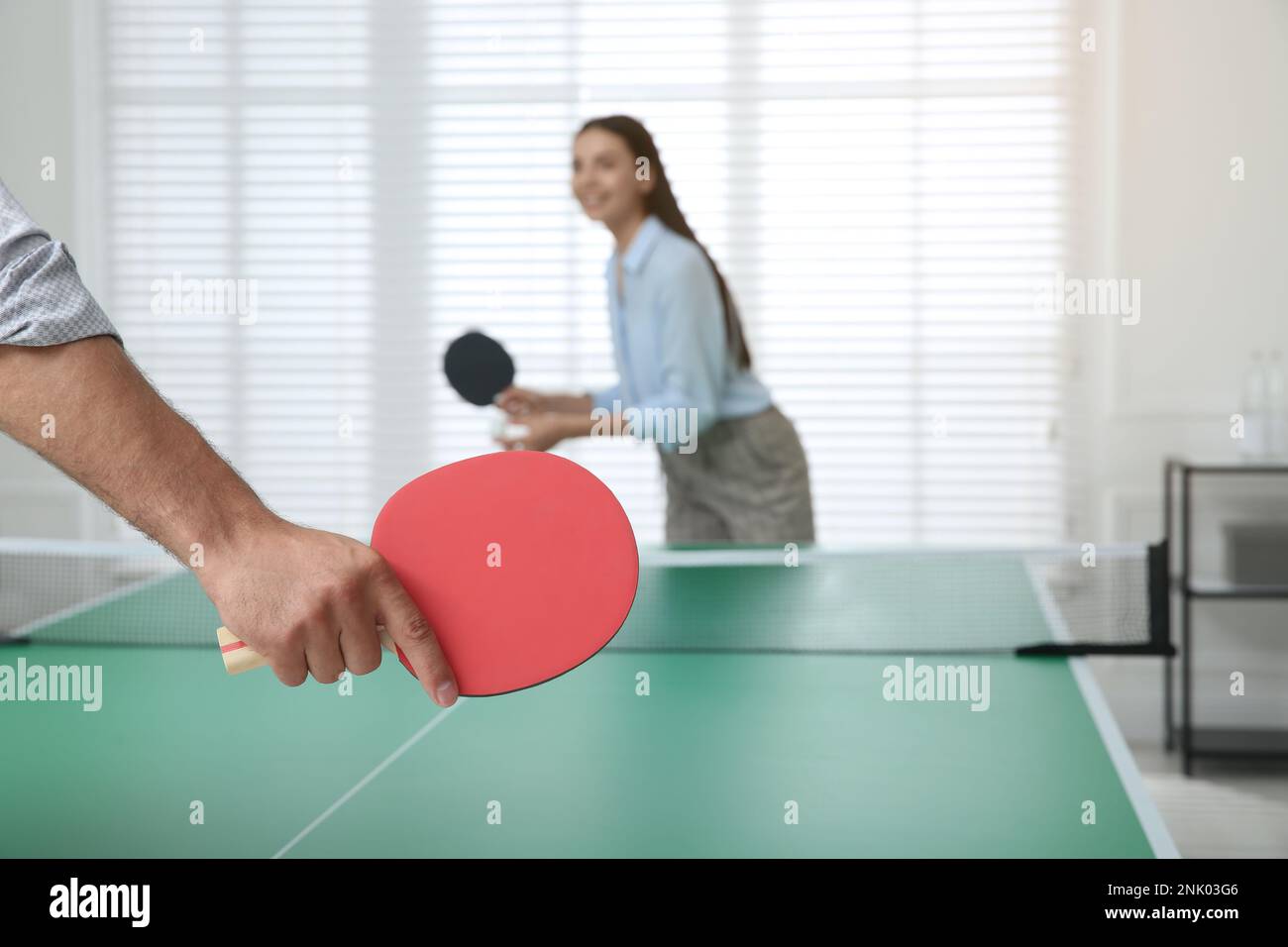 Business people playing ping pong in office, focus on tennis racket ...