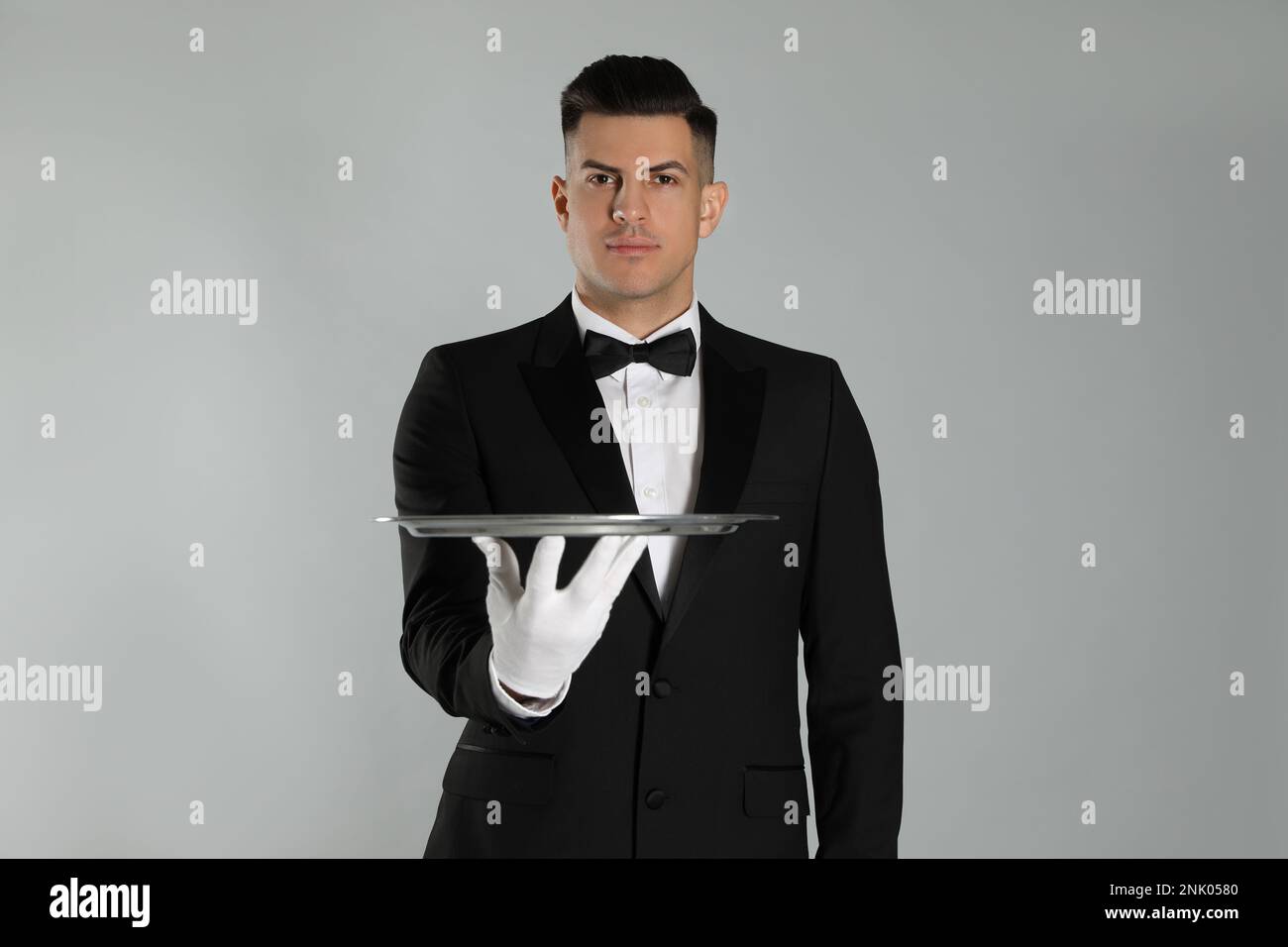 Handsome butler with tray on light grey background Stock Photo - Alamy
