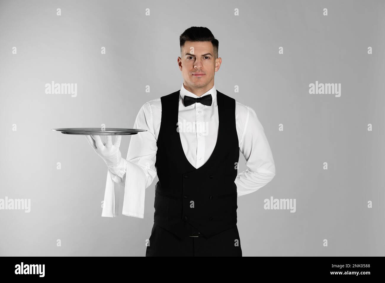 Handsome butler with tray on light grey background Stock Photo - Alamy