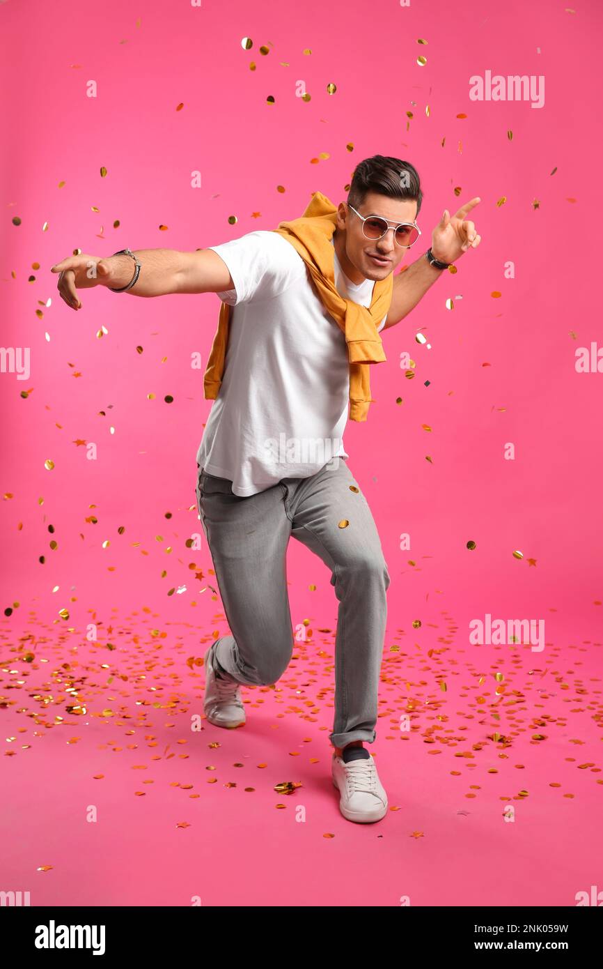 Happy man dancing and confetti on pink background Stock Photo - Alamy