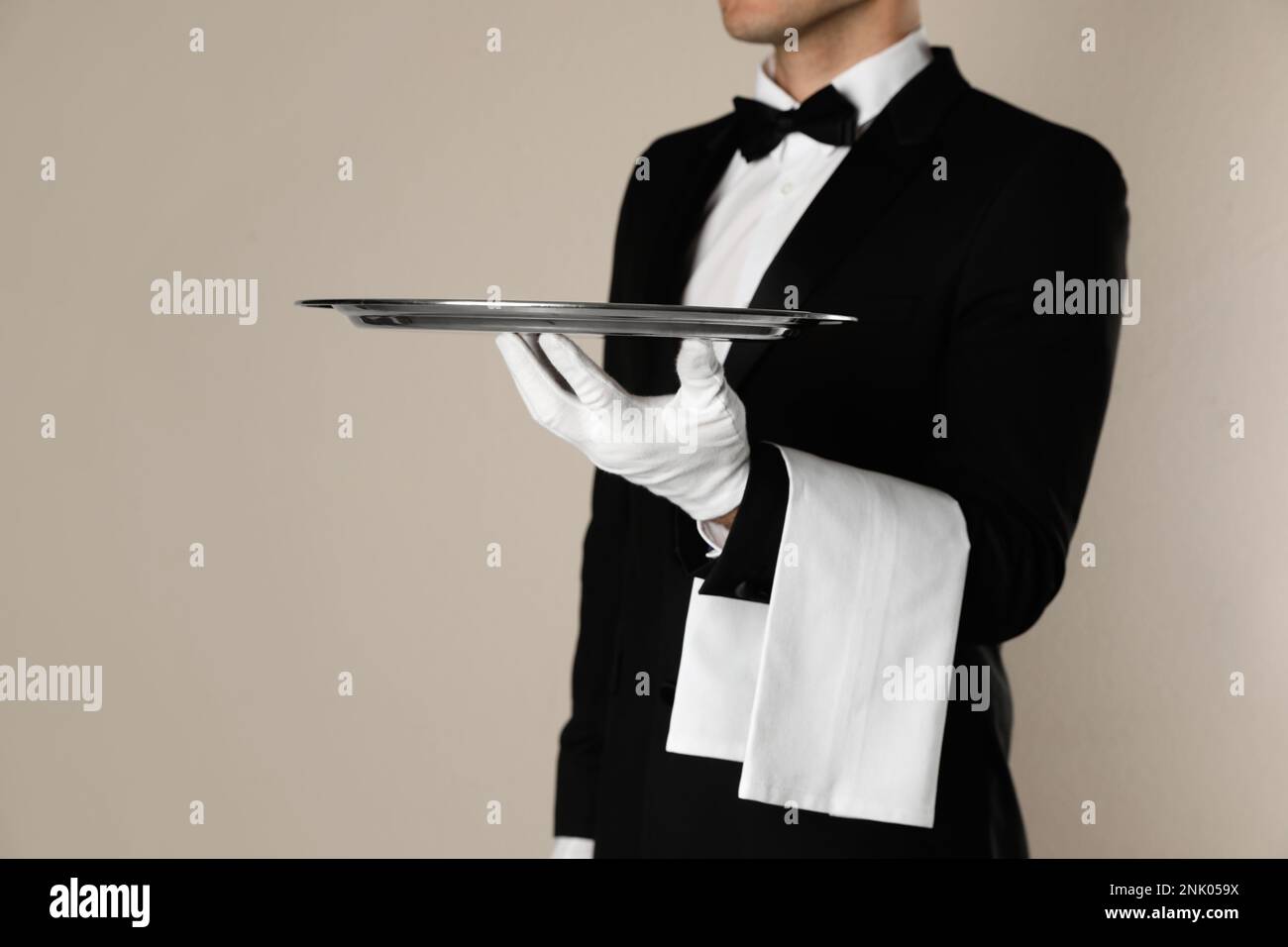 Butler with tray on beige background, closeup. Space for text Stock ...
