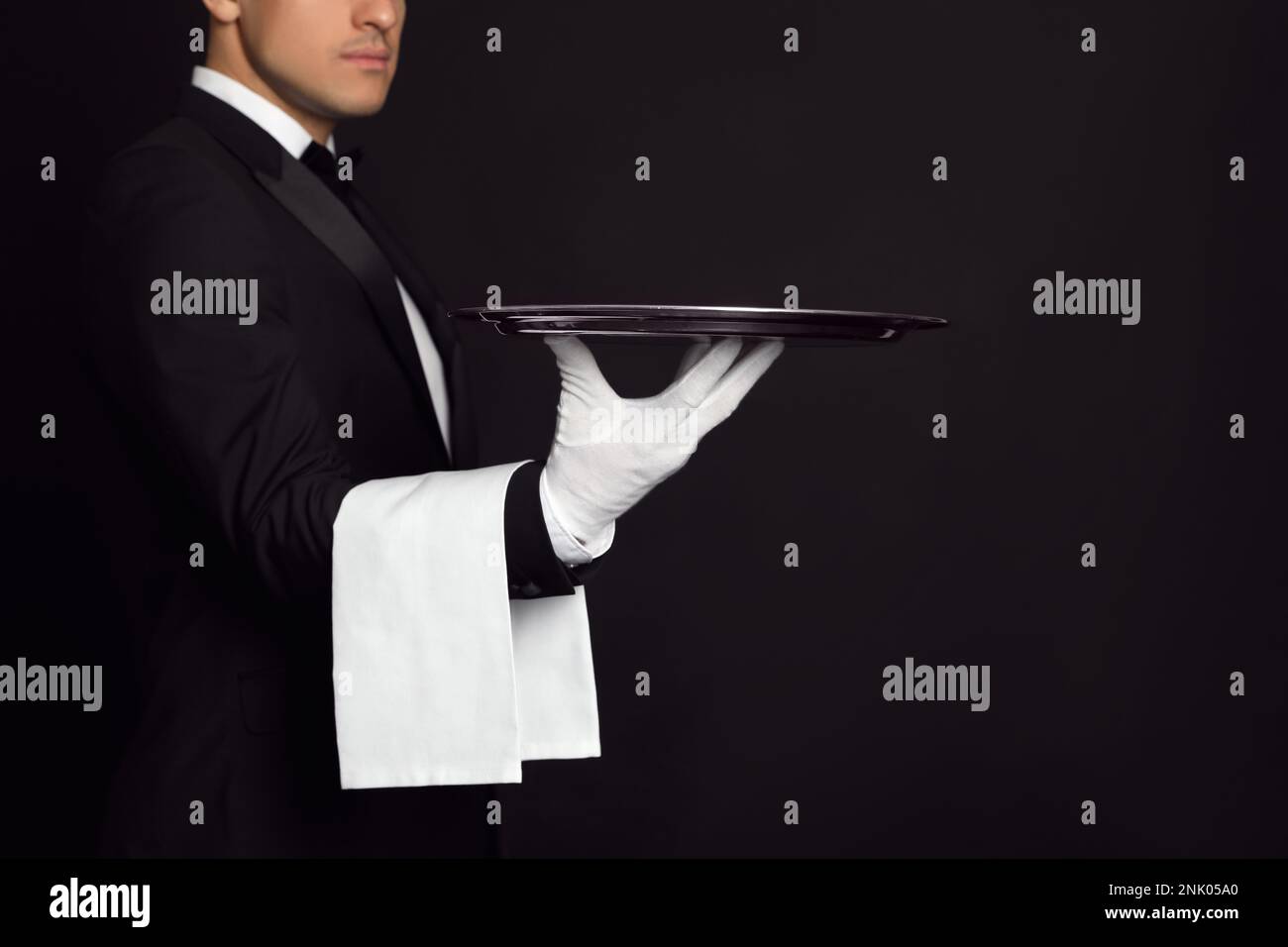 Butler with tray on black background, closeup. Space for text Stock ...