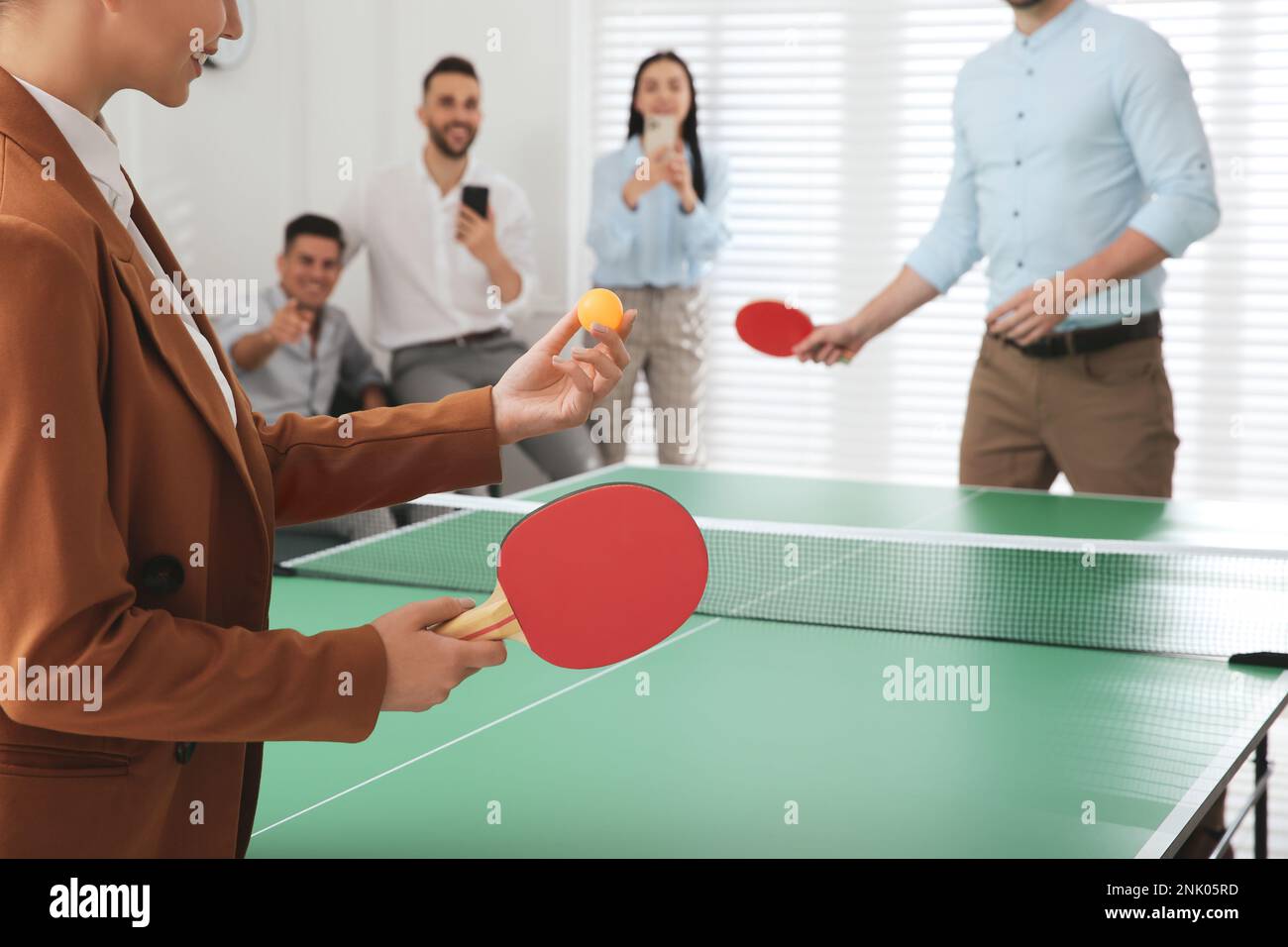 Business people playing ping pong in office, focus on tennis racket ...