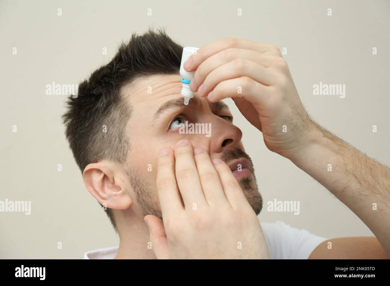Man using eye drops on beige background Stock Photo - Alamy