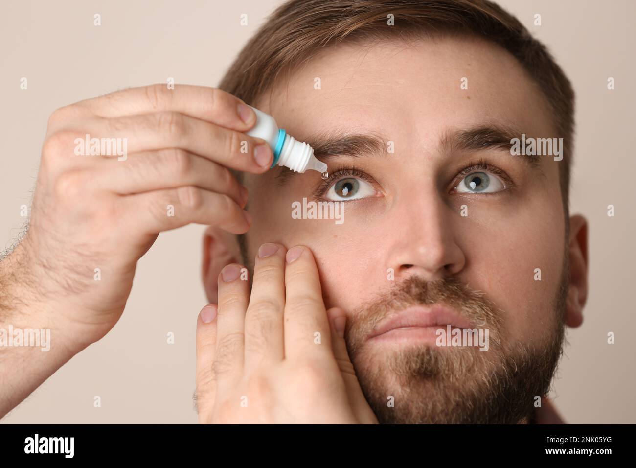 Young man using eye drops on beige background, closeup Stock Photo - Alamy