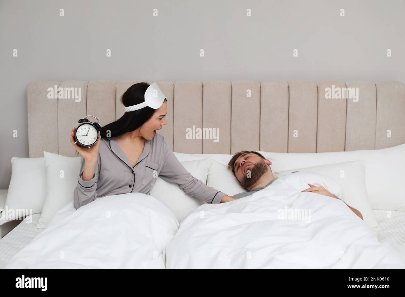 Emotional woman waking up man in bedroom. Being late concept Stock ...