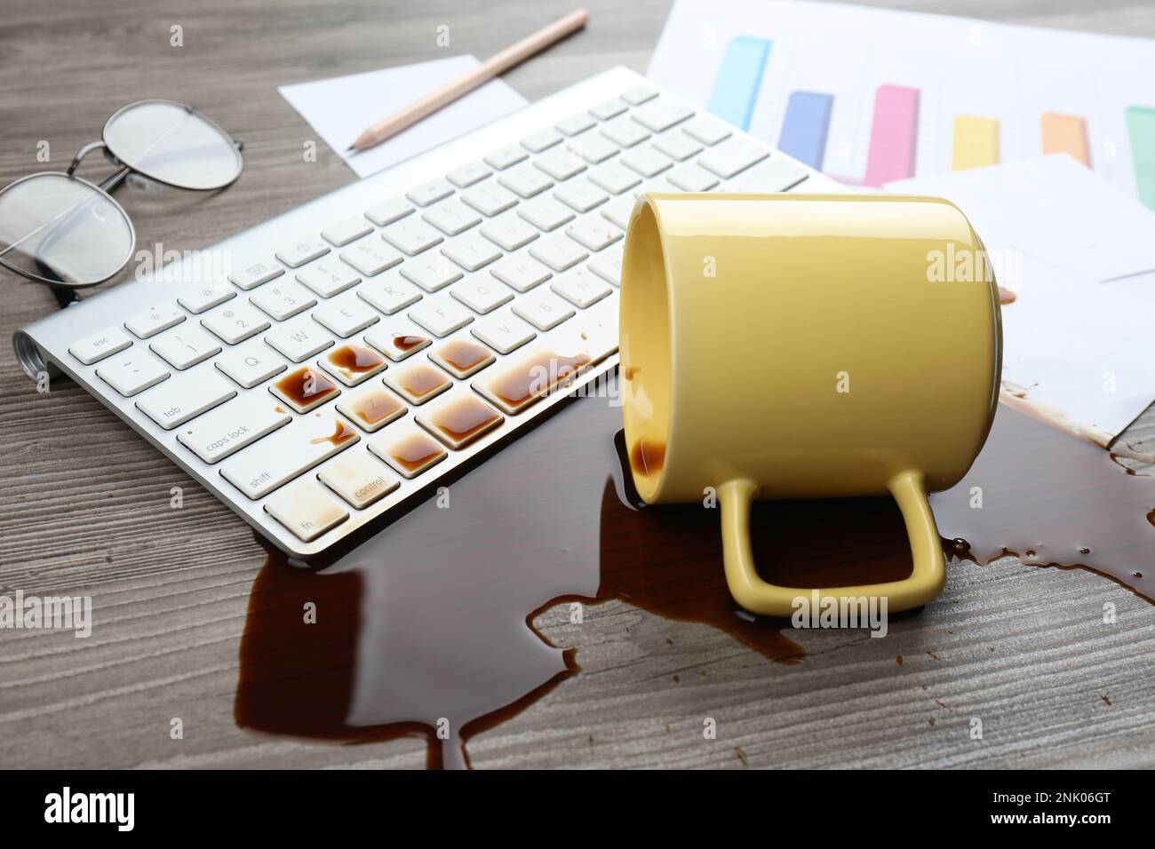 Cup of coffee spilled over computer keyboard on wooden office desk ...