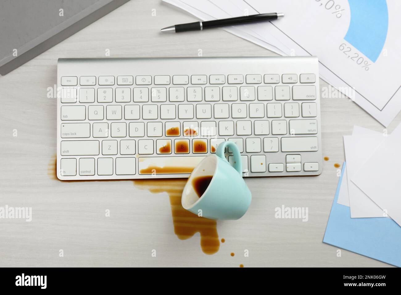 Cup of coffee spilled over computer keyboard on white office desk, flat ...