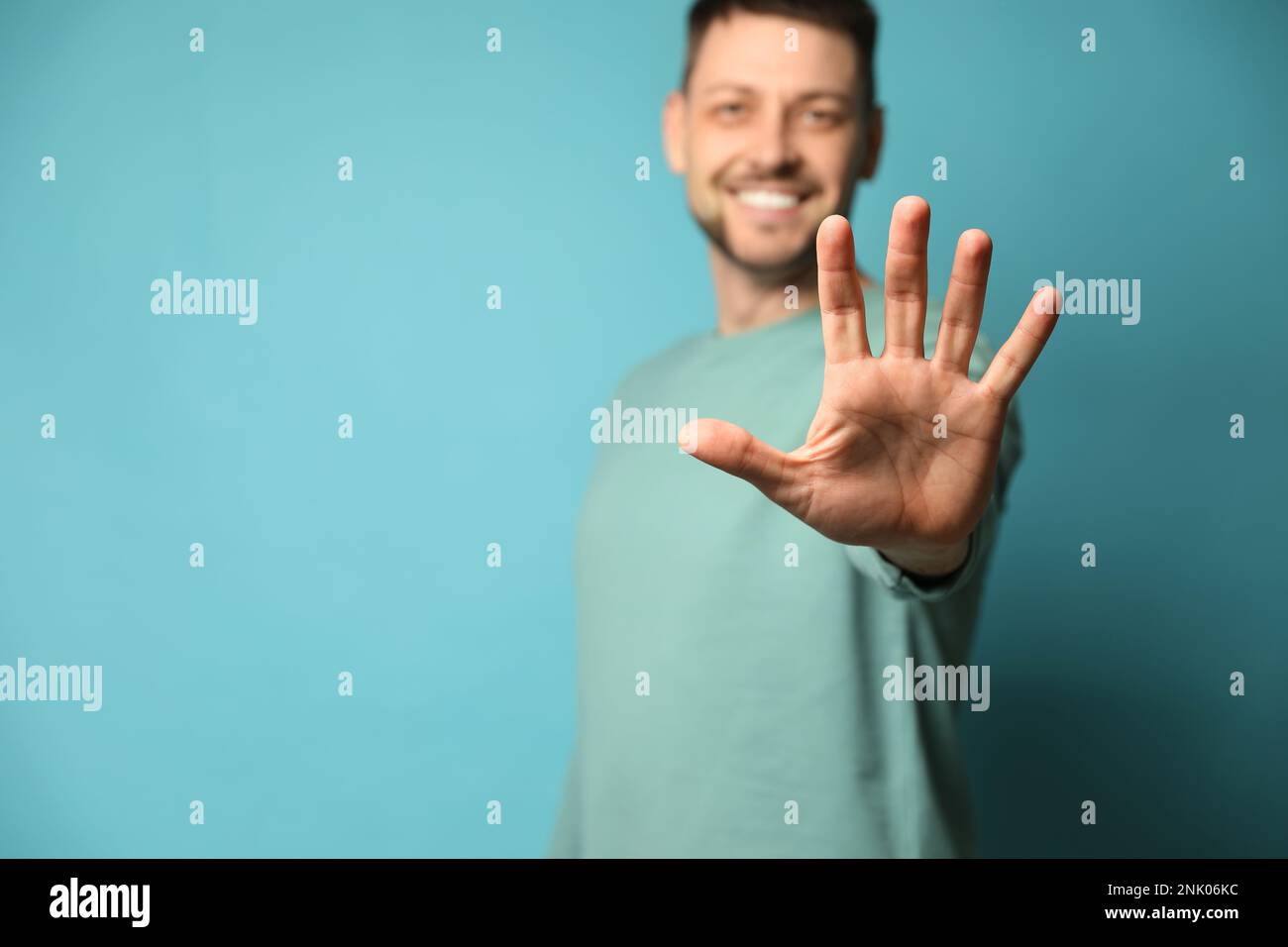 Left-handed man against light blue background, focus on palm. Space for ...