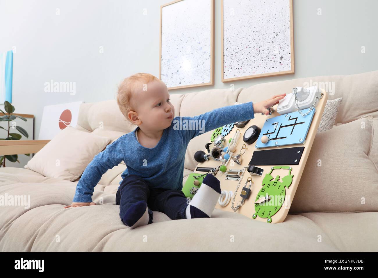 Cute little boy playing with busy board on sofa at home Stock Photo - Alamy