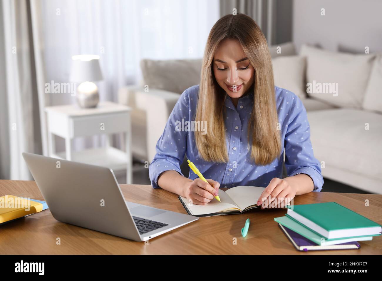 Young woman writing down notes during webinar at table in room Stock ...