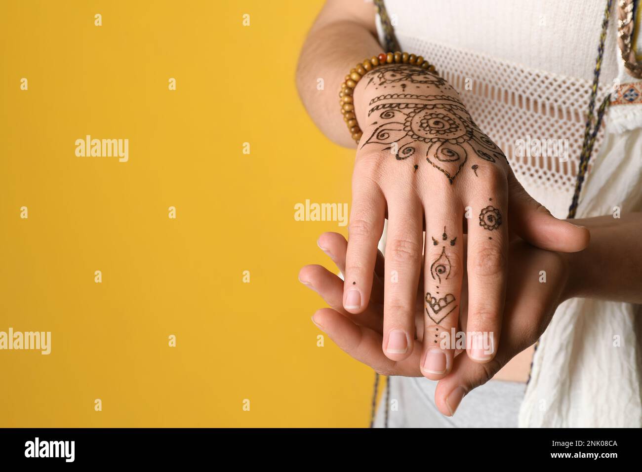 Woman with beautiful henna tattoo on hand against yellow background ...