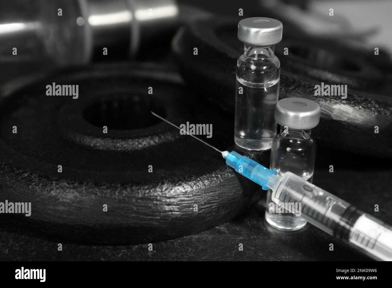 Vials and syringe with drug near sports equipment on table, closeup ...