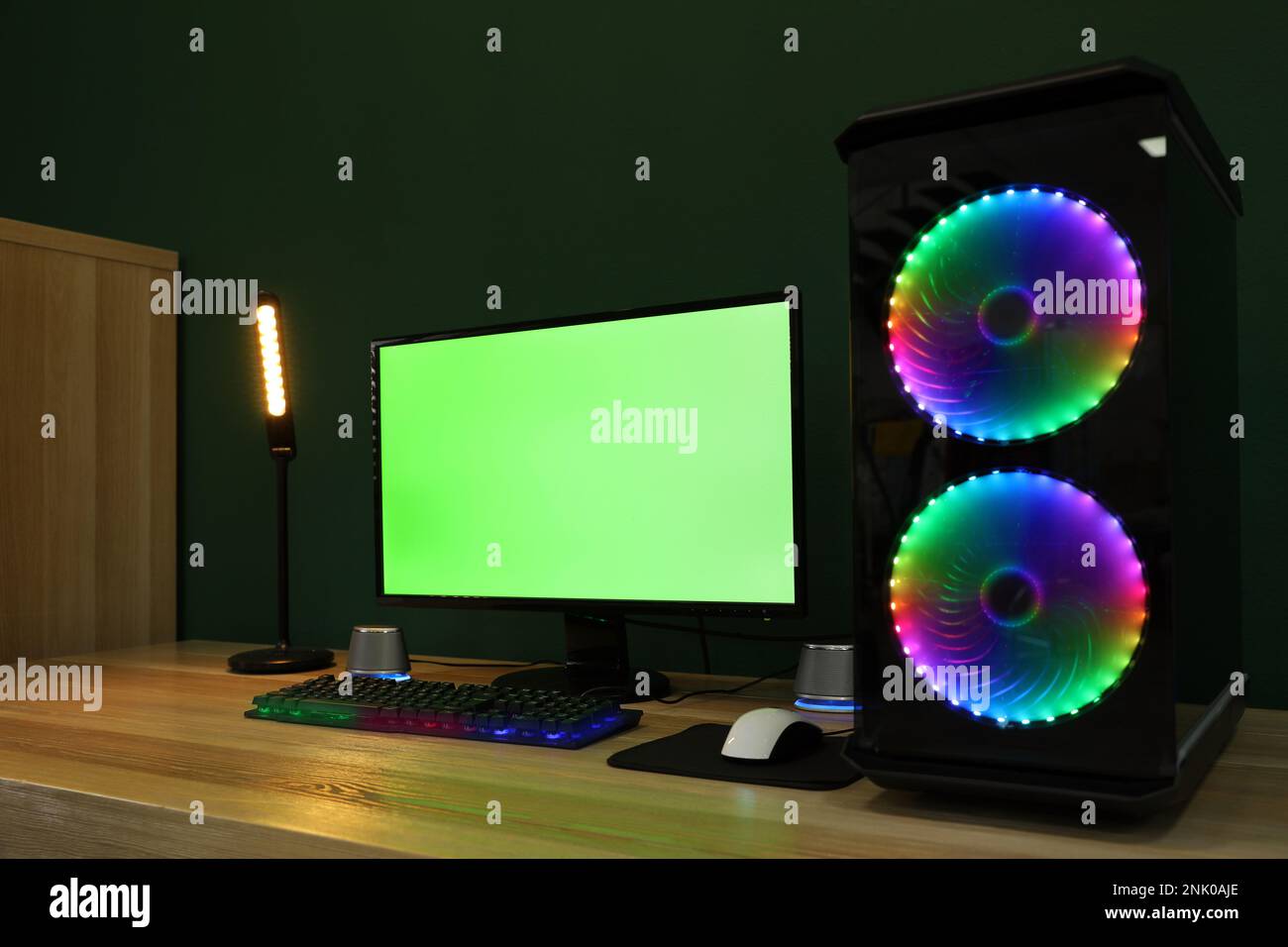 Modern computer and RGB keyboard on wooden table indoors. Mockup green ...