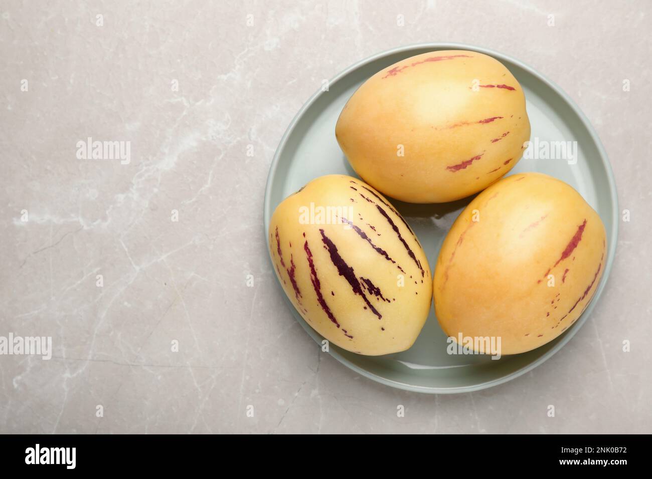 Fresh ripe pepino melons on light table, top view. Space for text Stock ...