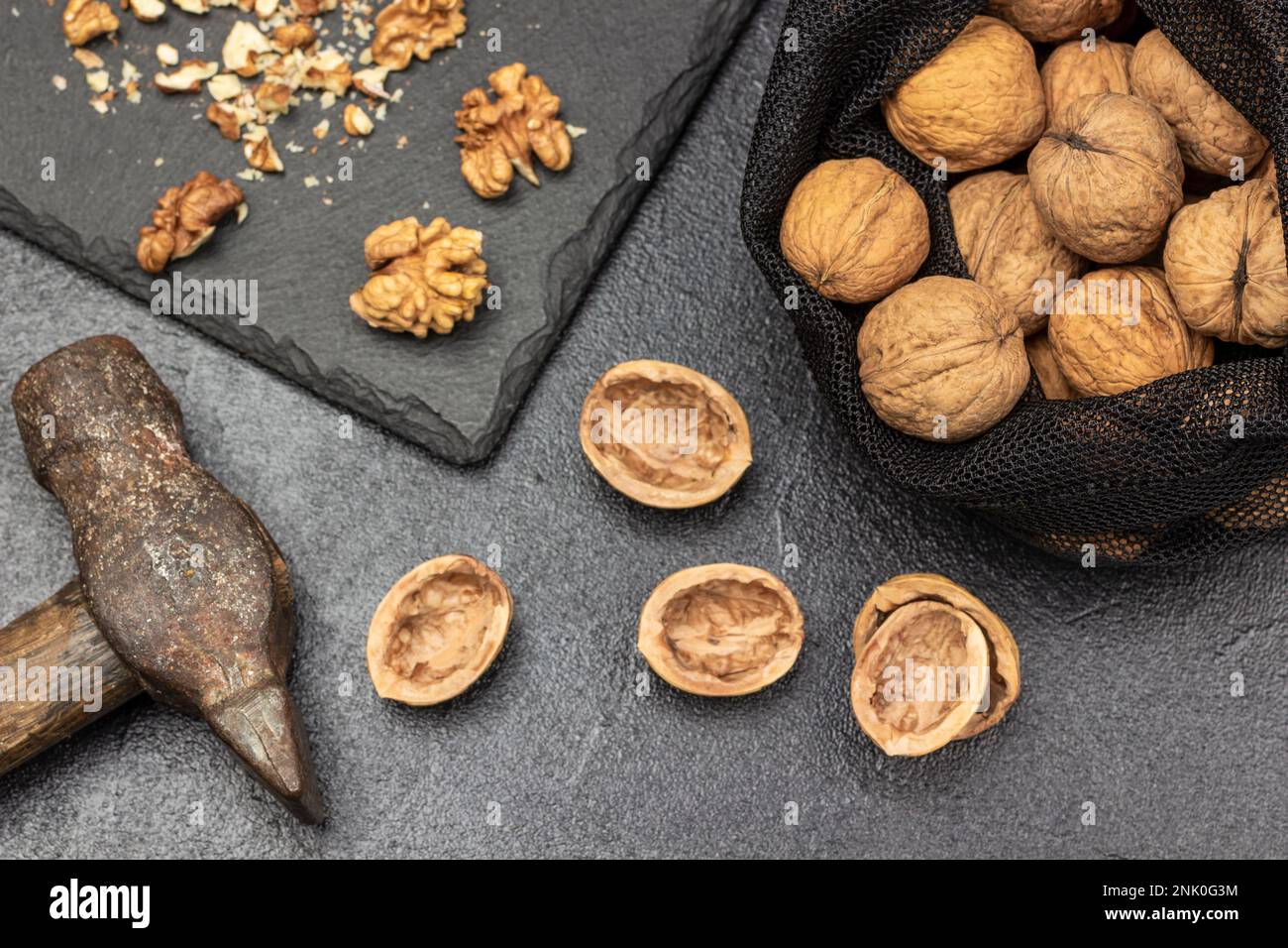 Walnuts in a reusable bag. Hammer, nut shells on the table and nut ...