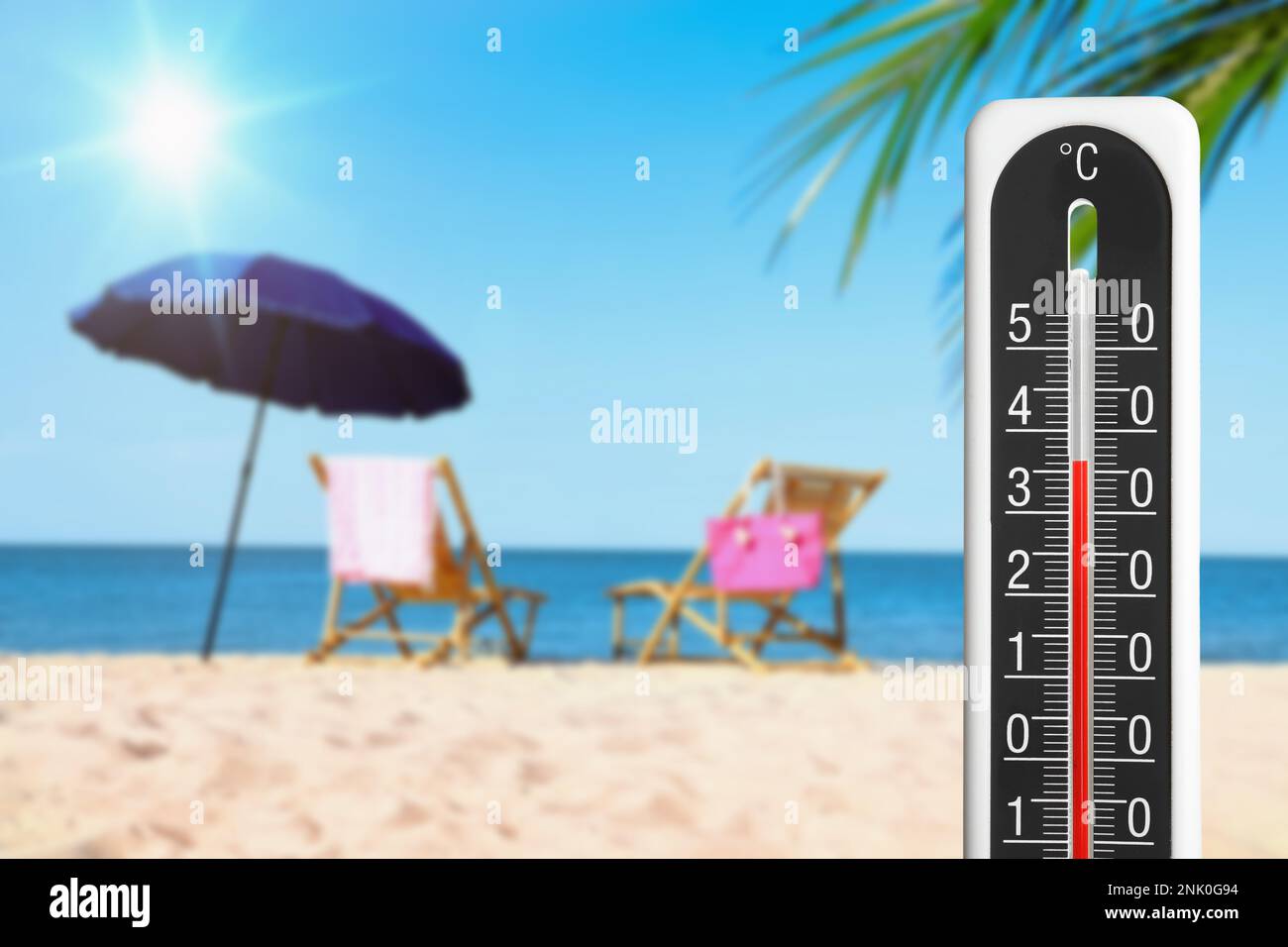 Weather thermometer and beautiful sandy beach with wooden sunbeds on ...