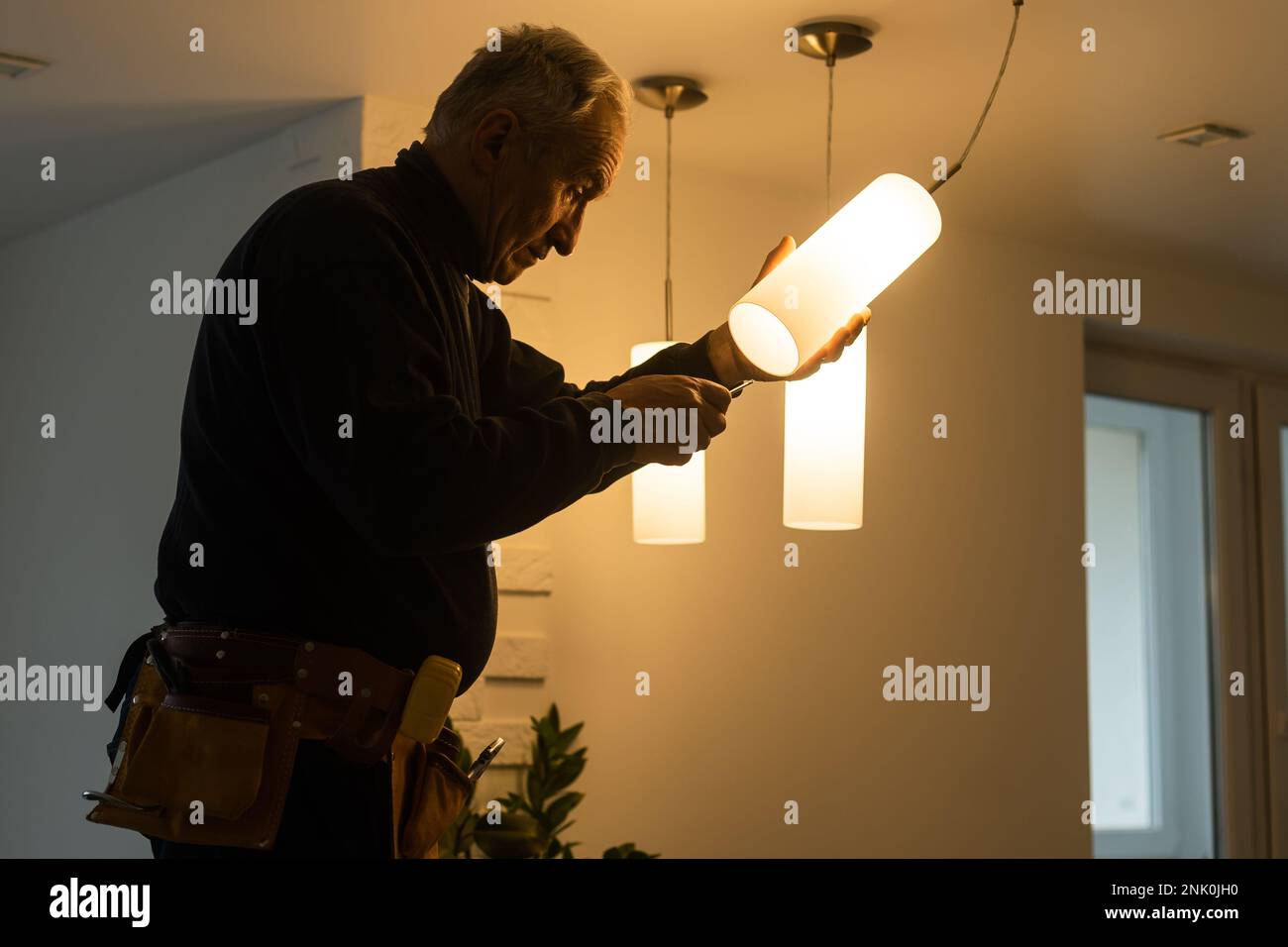 A male electrician changes the light bulbs in the ceiling light. men's ...