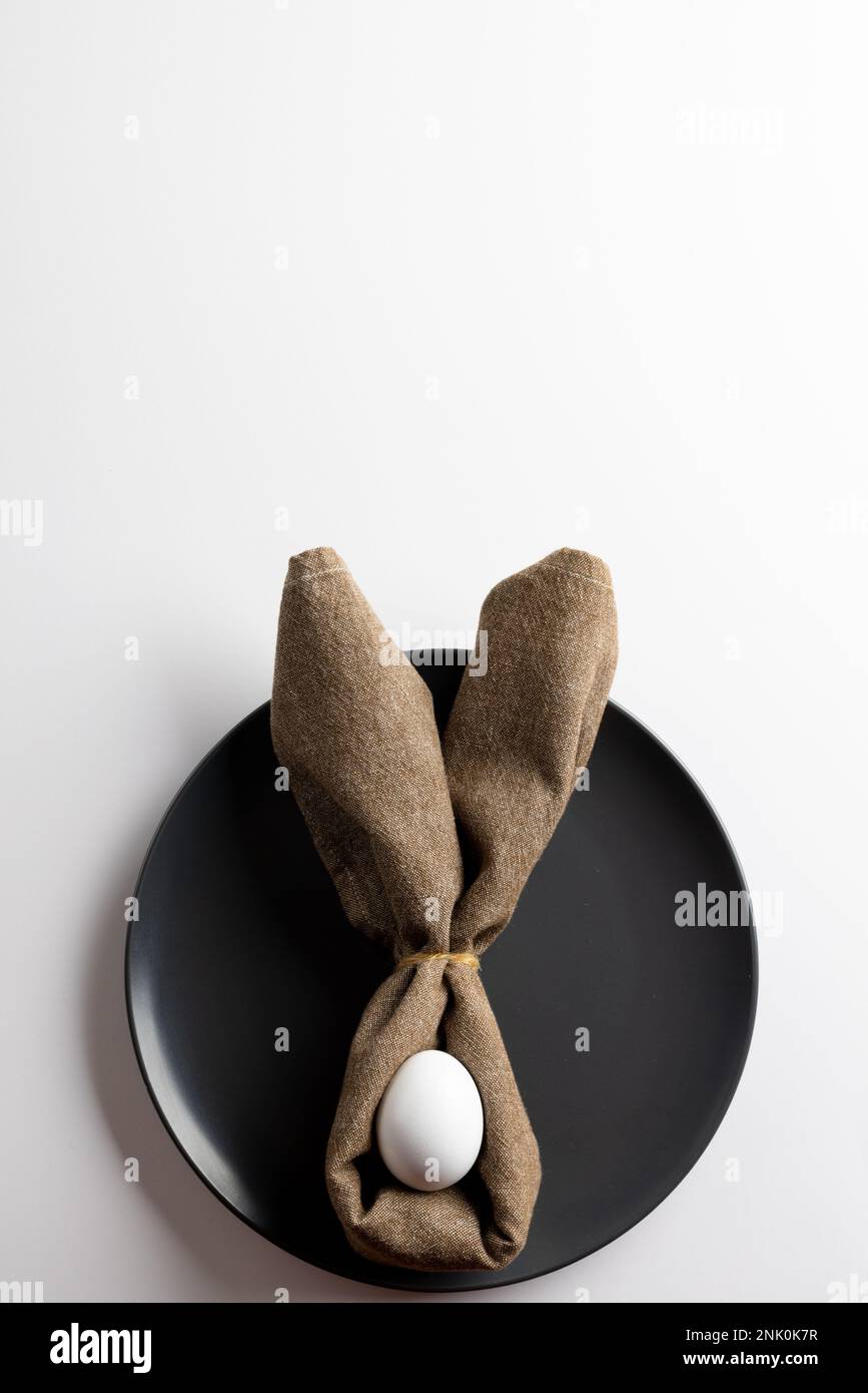 Image of white easter egg and bunny ears on black plate and copy space ...