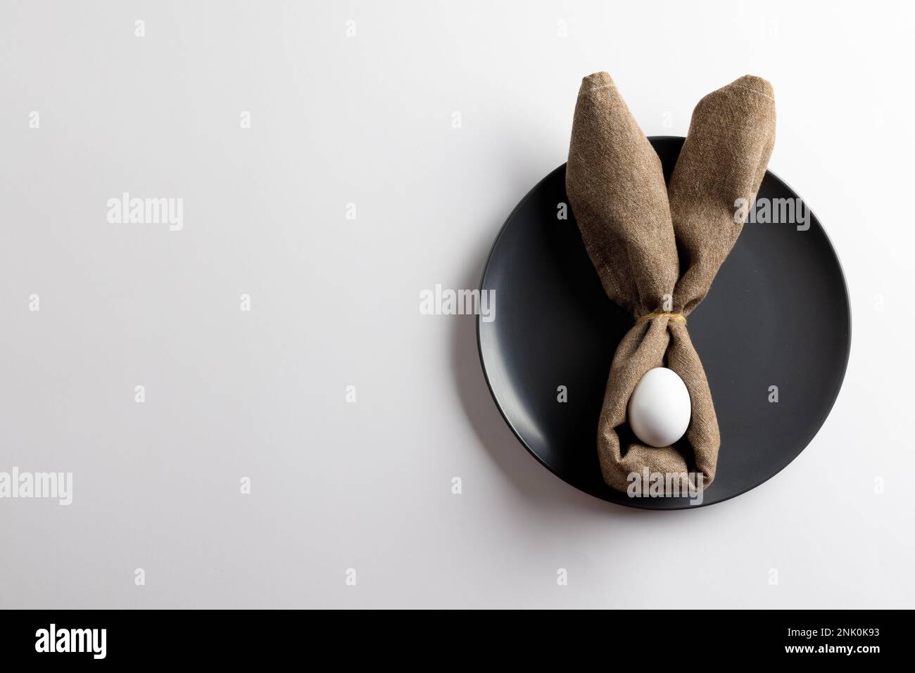 Image of white easter egg and bunny ears on black plate and copy space ...