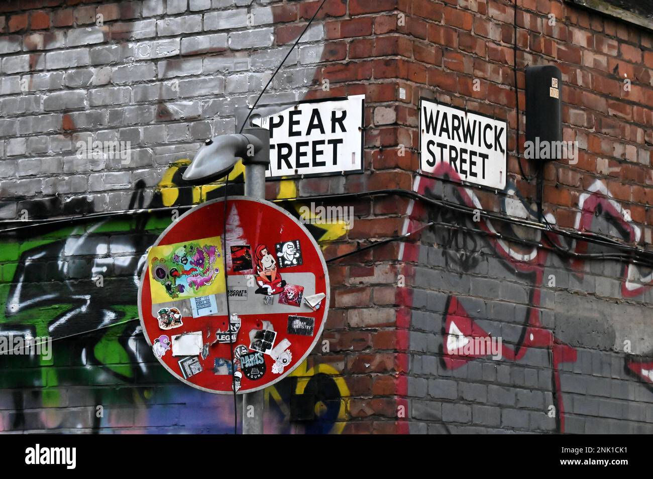 Graffiti and stickers on a no entry sign at the corner of a street in ...