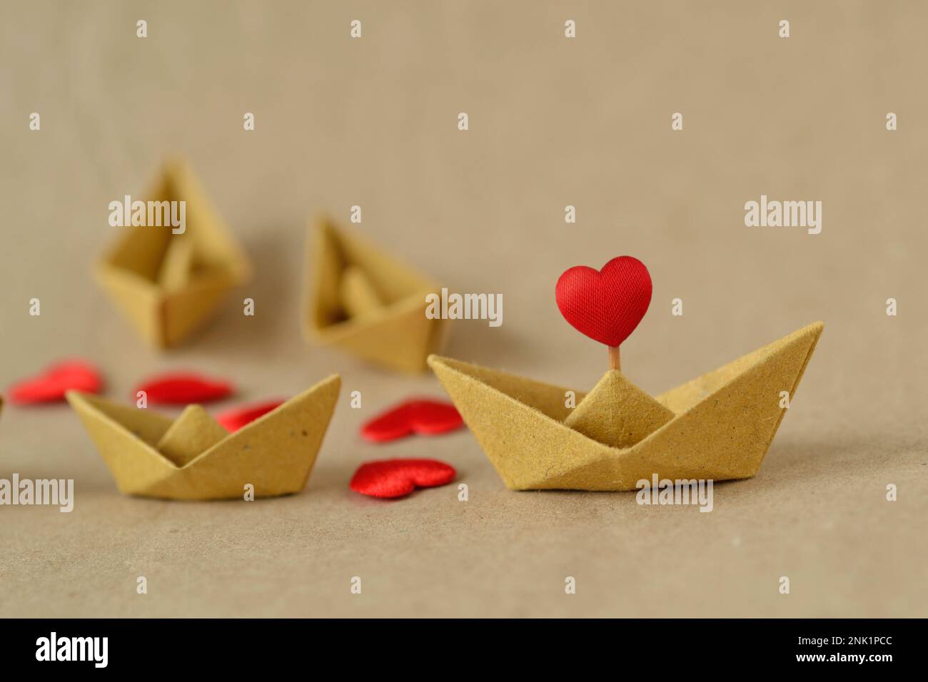 Origami recycled paper boat with heart leading a group of boats ...