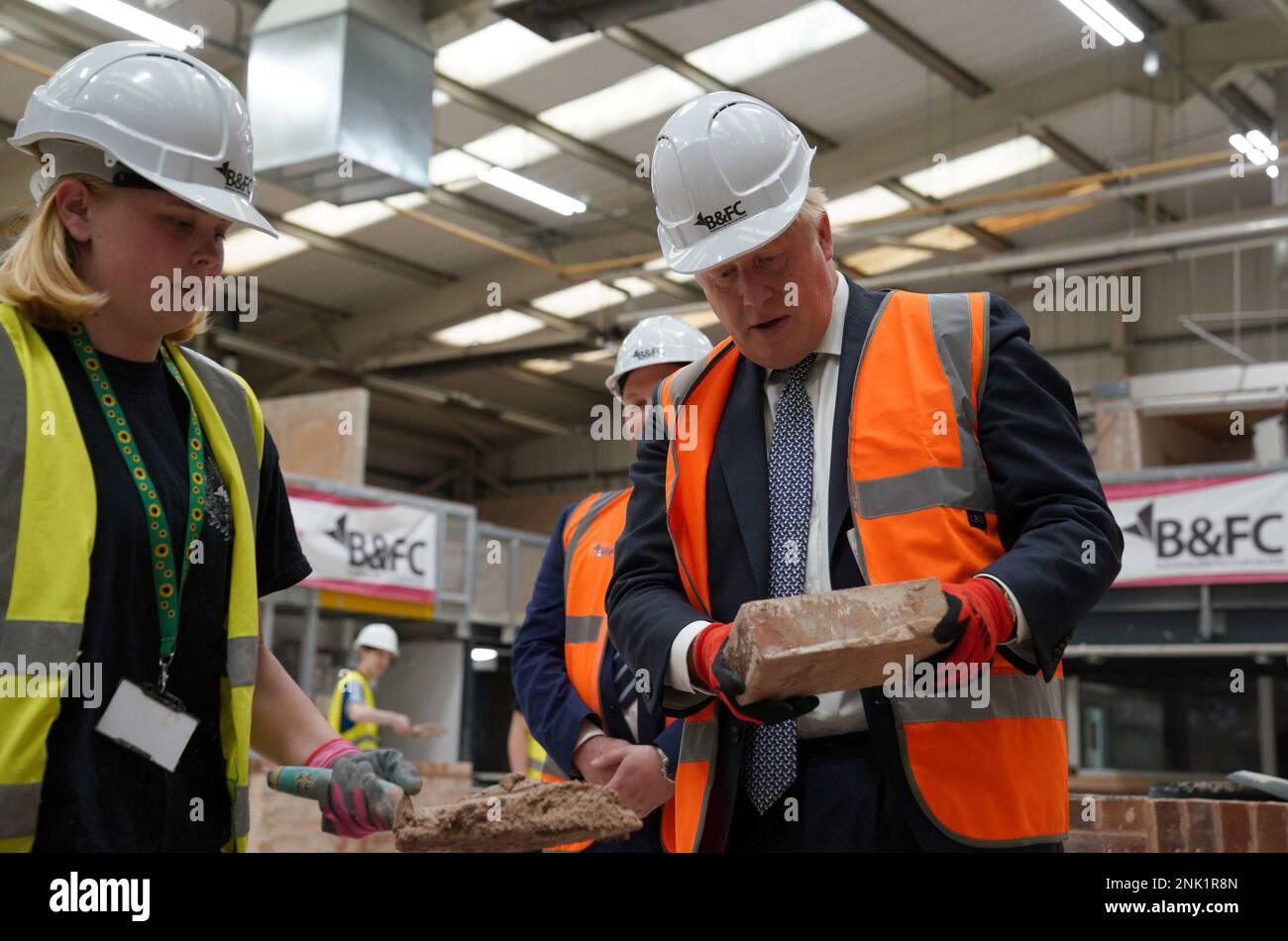 Britain's Prime Minister Boris Johnson, right, joins a brick laying ...