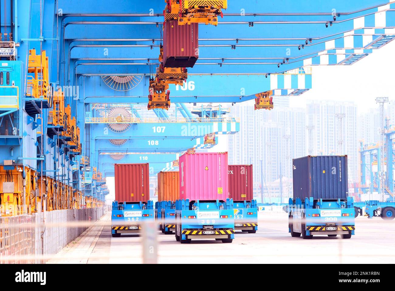 Automated transporters and cranes work on a container dockyard in ...