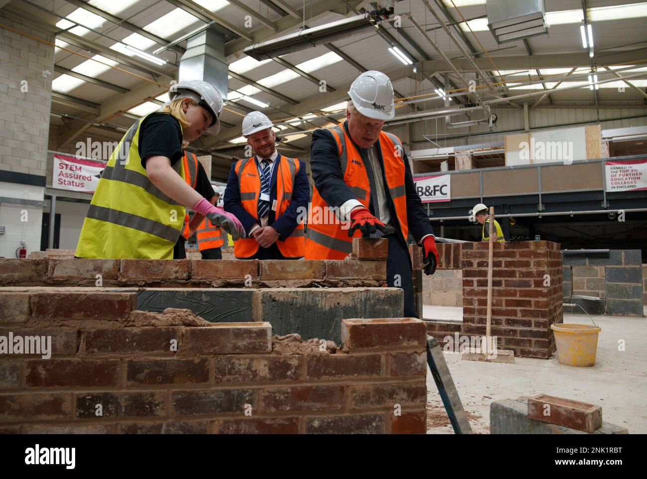 Britain's Prime Minister Boris Johnson, right, joins a brick laying ...