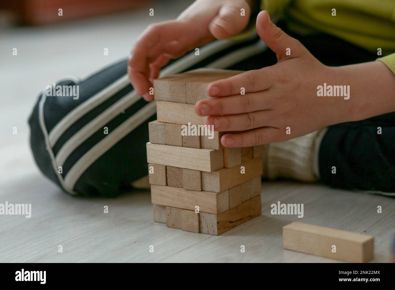 The child plays in a tower of wooden bars. Floors of wooden pieces. The ...