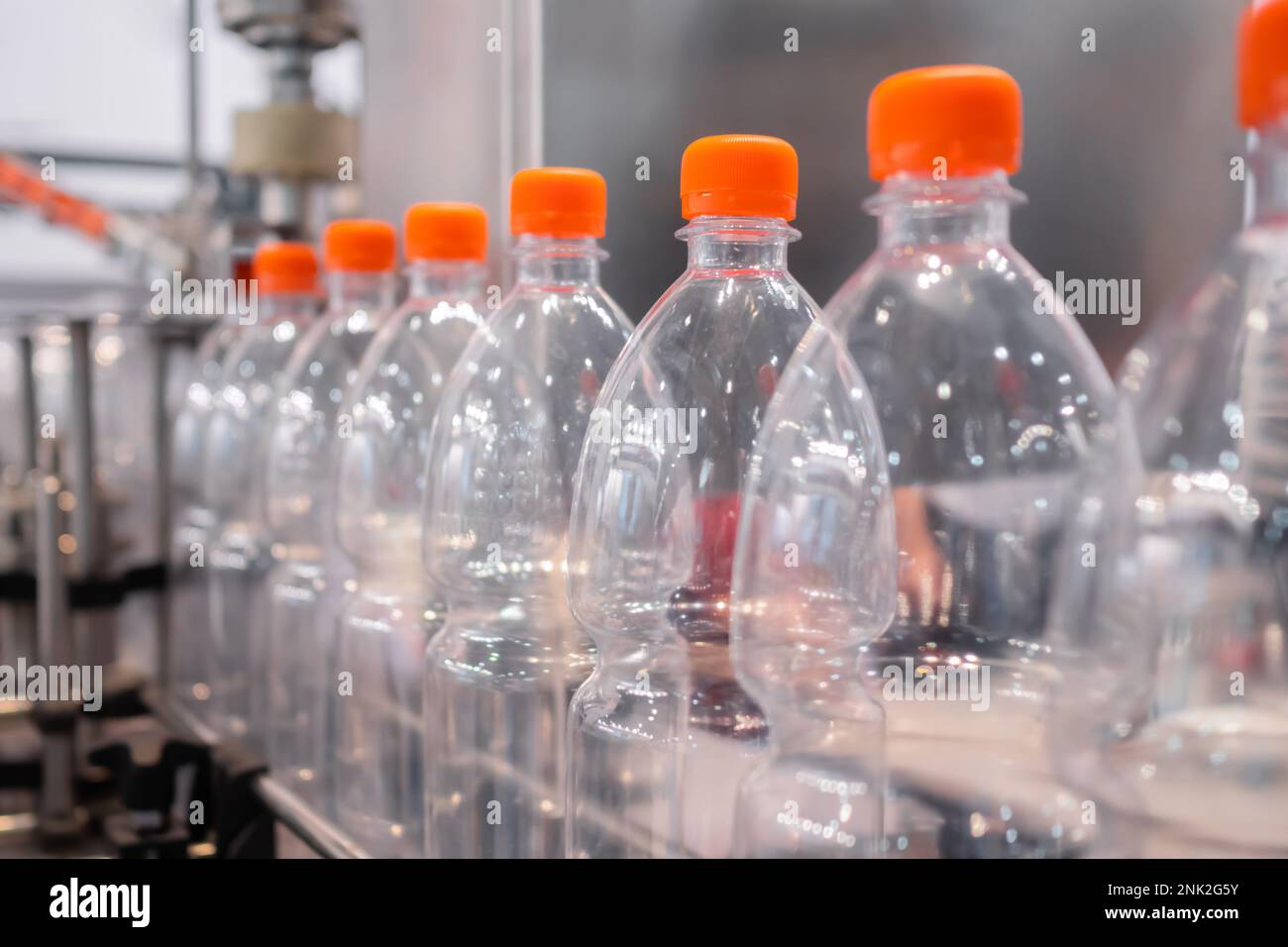 Row of empty pet lemonade bottles with orange caps on conveyor belt ...