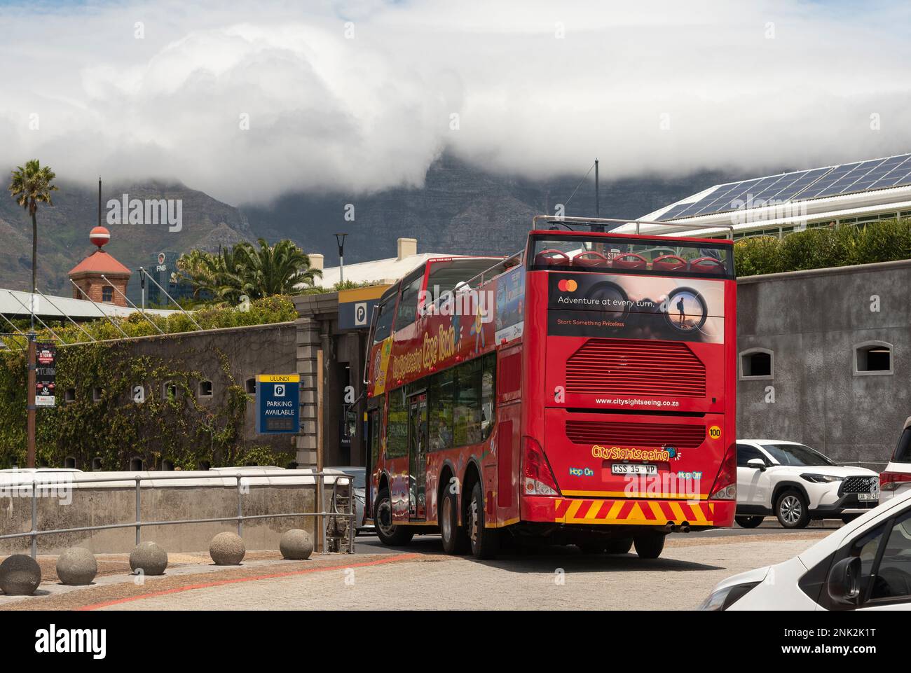 Cape Town South Africa. 2023. A red tourist open top bus making a lefthand turn in a busy street ...