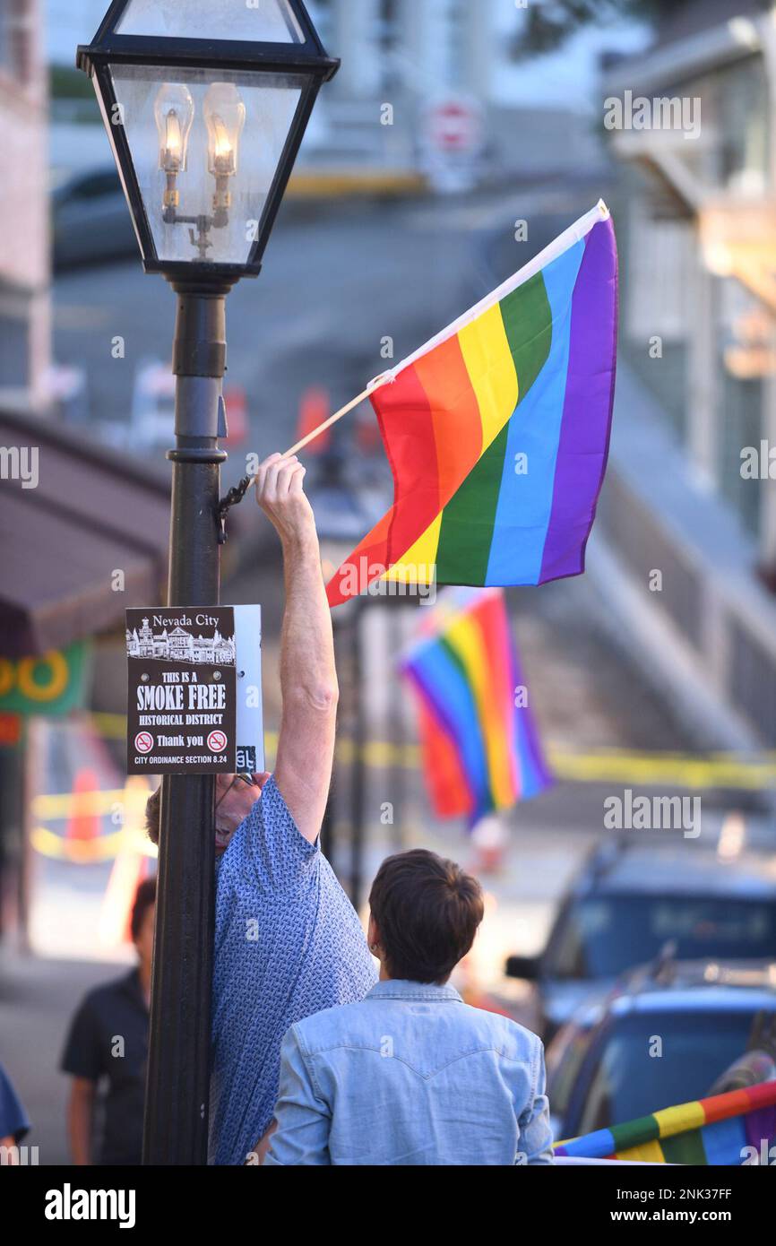 Pride flags are hung on posts along Pine Street Tuesday by members of ...