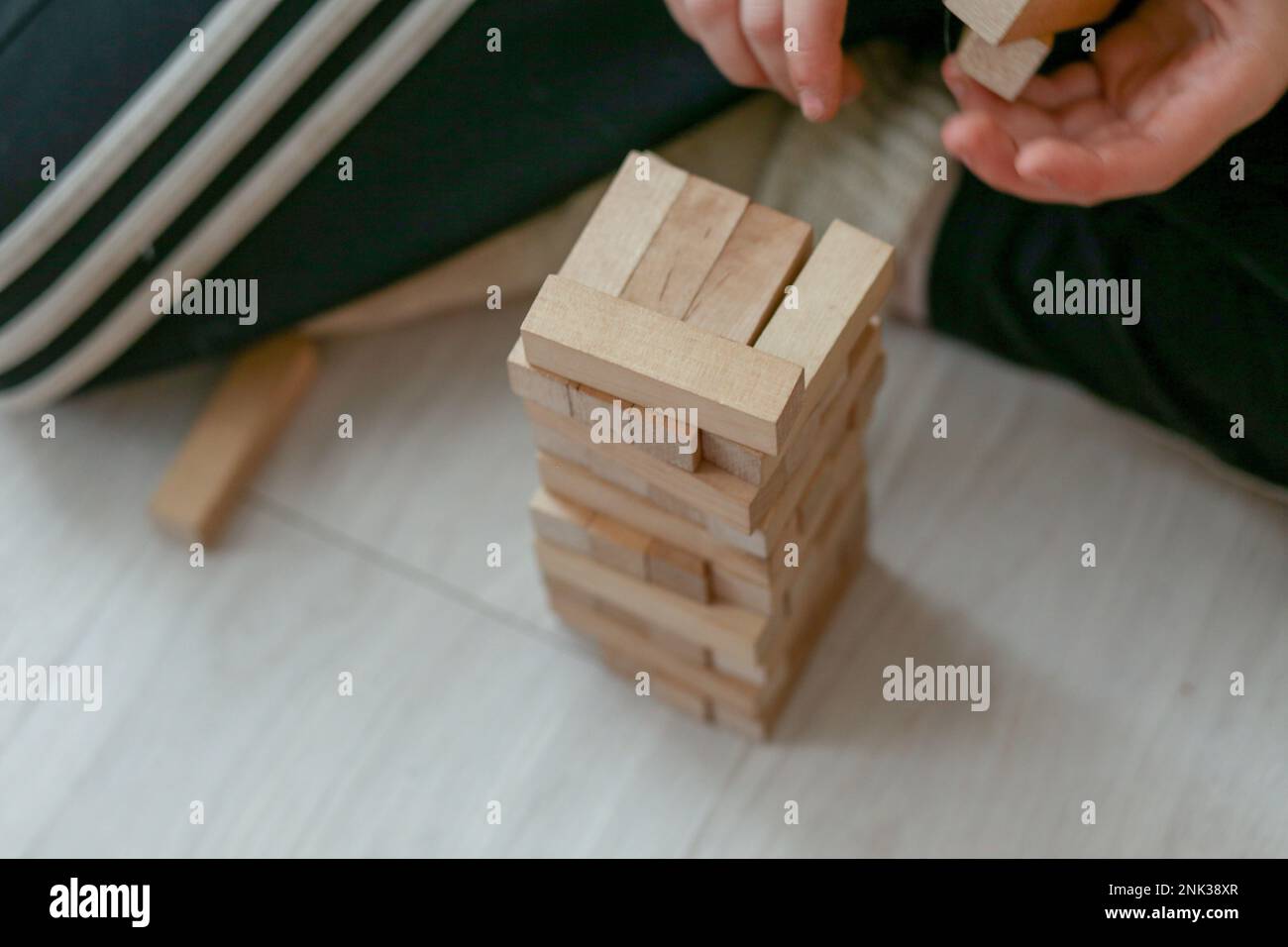 The child plays in a tower of wooden bars. Floors of wooden pieces. The ...