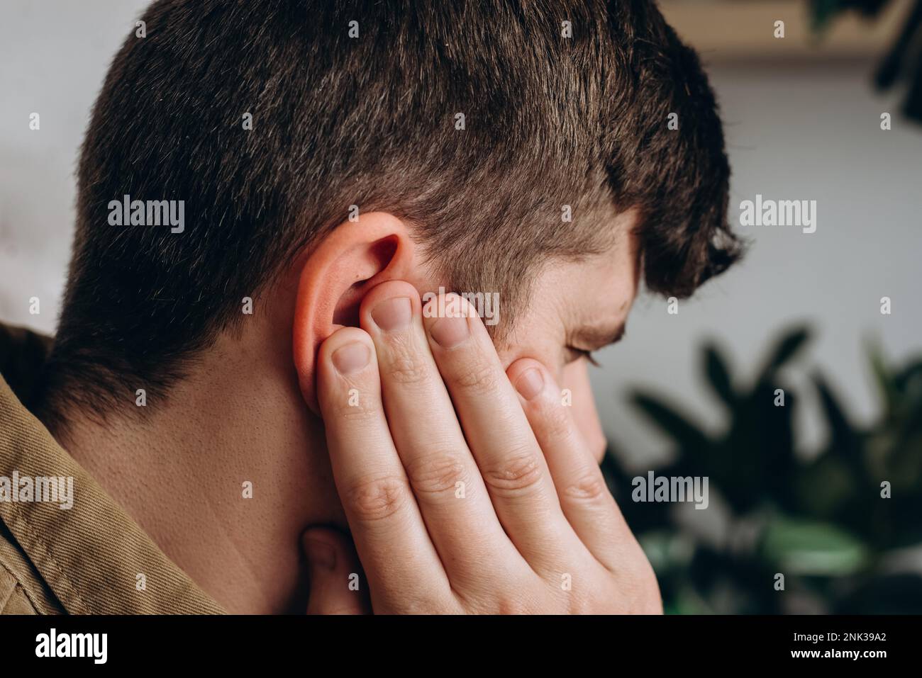Closeup up of upset young male having ear pain touching painful head ...