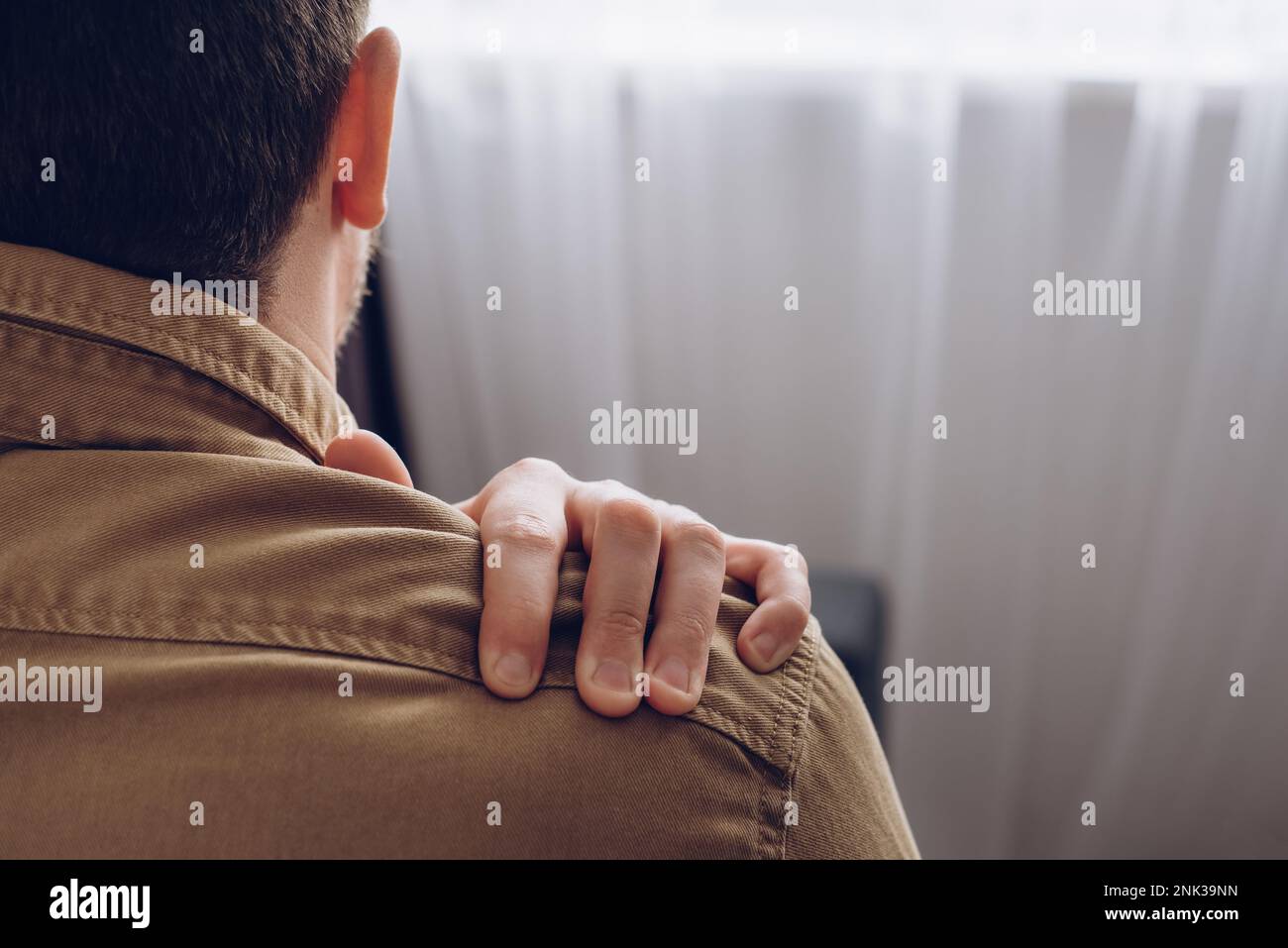 Side view of unhealthy young man sitting near window suffering from ...