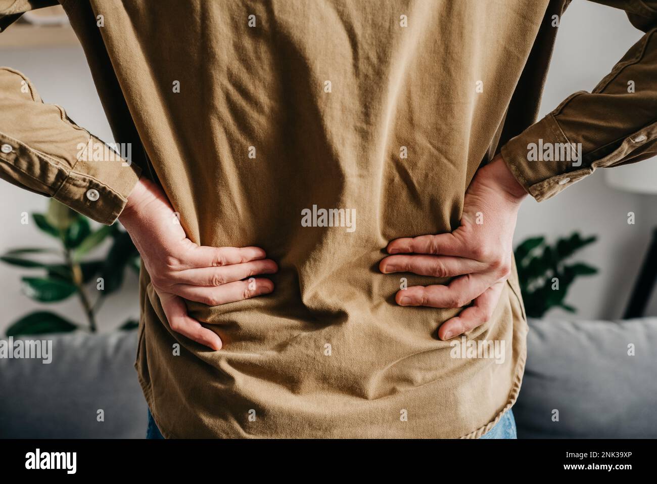 Back view of unhealthy young caucasian man 30s in brown shirt touching ...