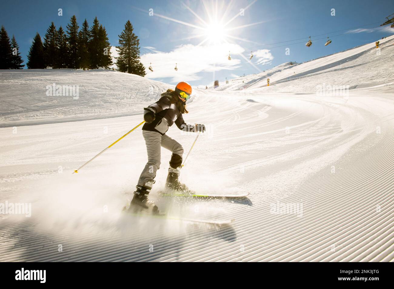 A single girl enjoys a sunny winter day of skiing, dressed in full snow ...
