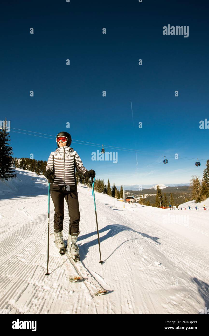 A single young female enjoys a sunny winter day of skiing, dressed in ...