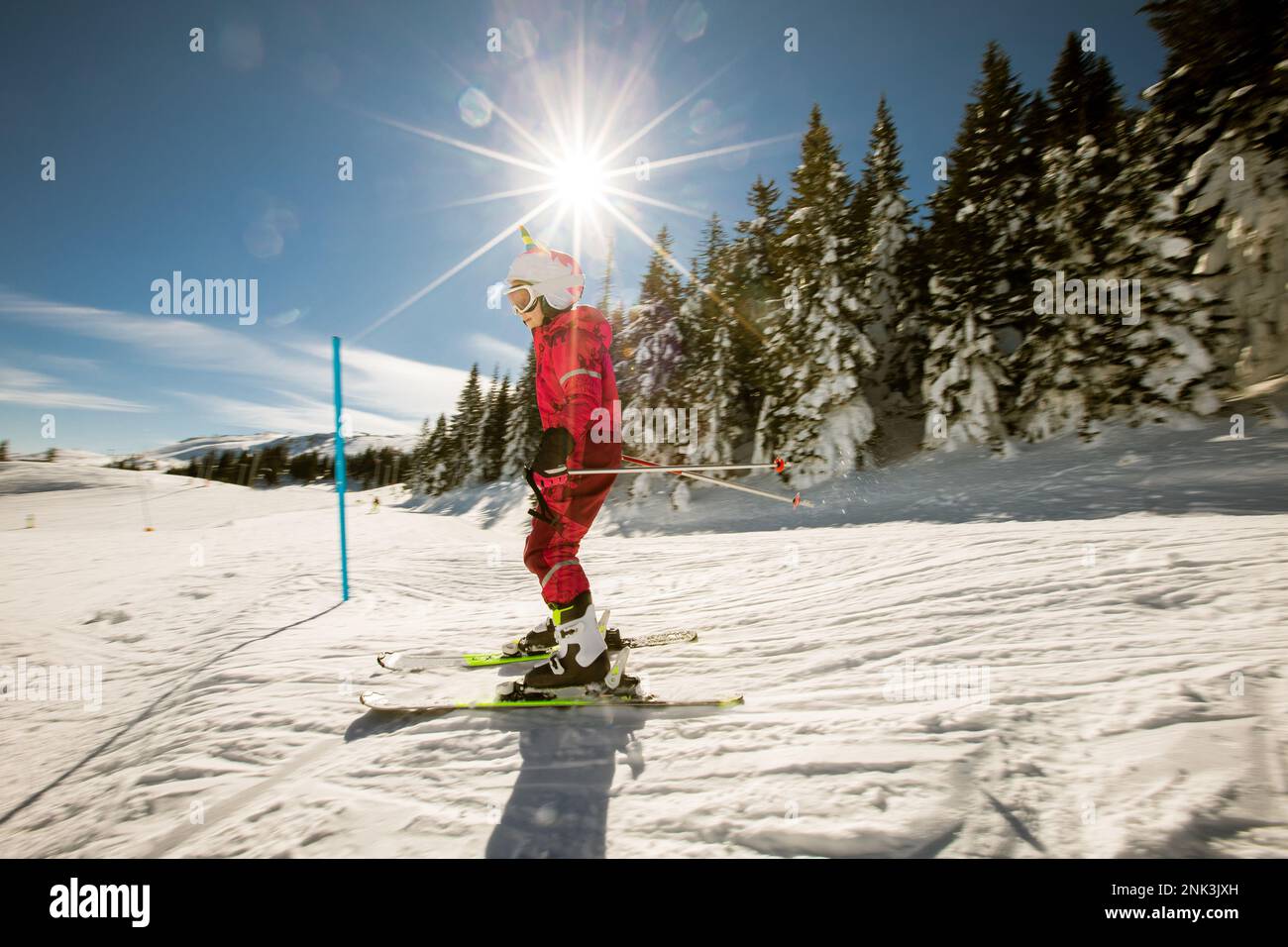 A single girl enjoys a sunny winter day of skiing, dressed in full snow ...