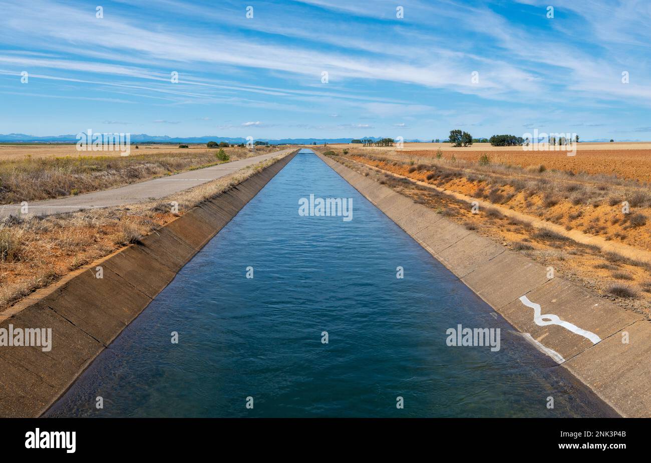 A long, straight irrigation canal in Spain stretches into the distance ...
