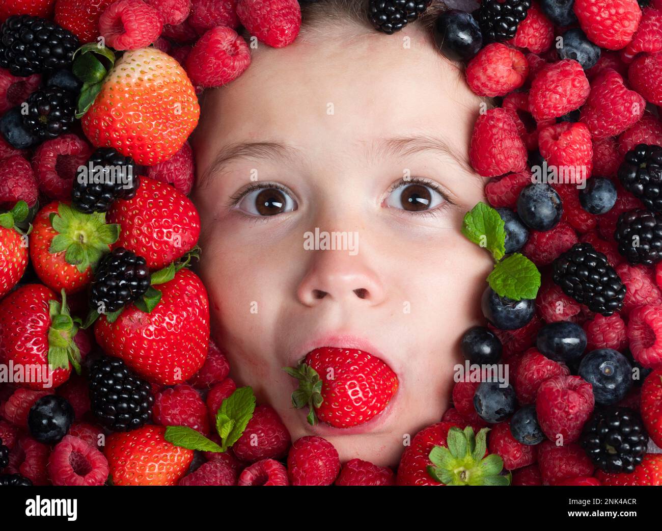 Top view photo of child face with berri. Berry set near kids face. Cute ...